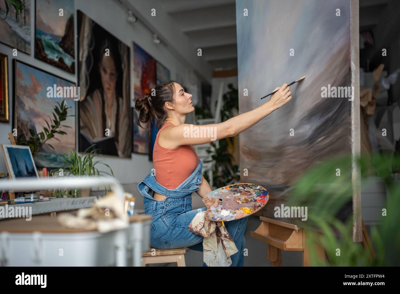 Woman artist paints landscape on canvas of easel in bright design ...
