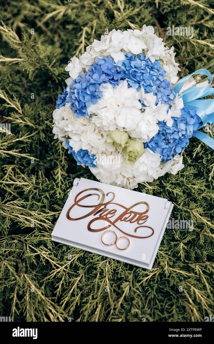 Elegant wedding details with floral bouquet and 'One Love' sign ...