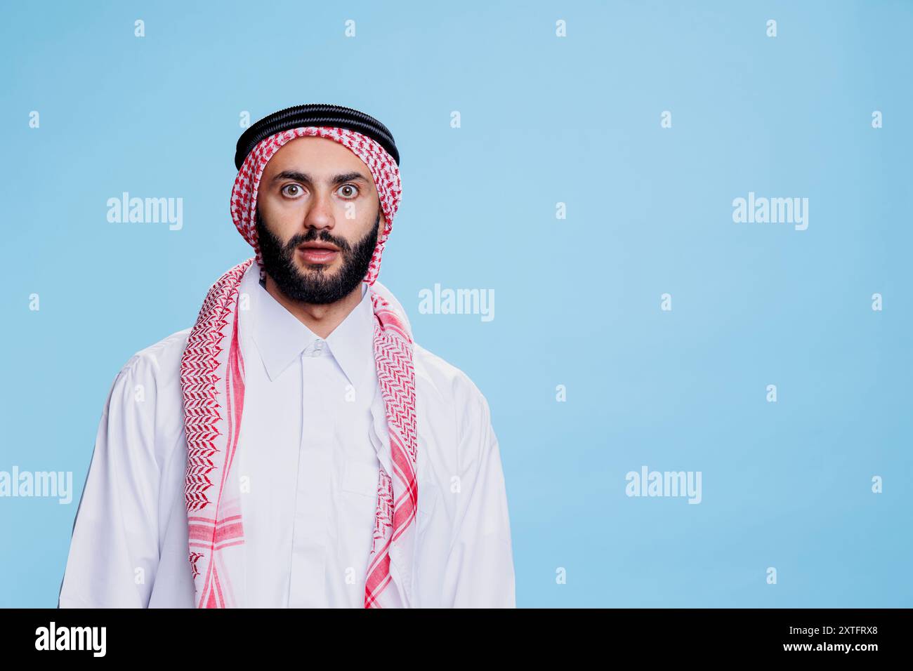 Surprised muslim man dressed in traditional clothes looking at camera ...