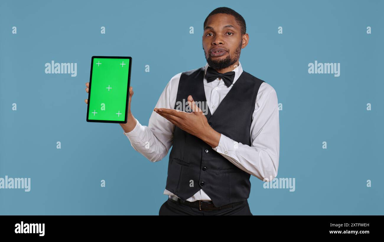 Bellman hotelier showing a tablet with green screen display in studio ...