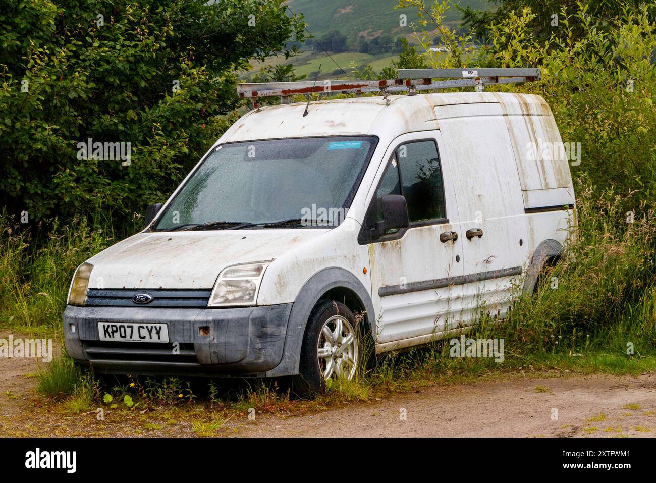 Old and abandoned white Foed Connect van parked on a dirt road ...