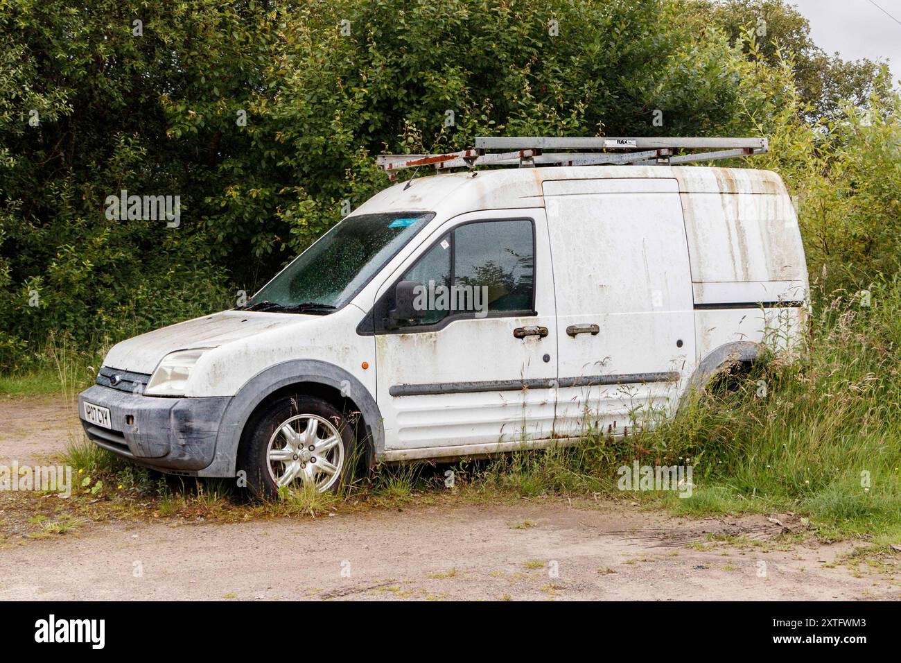 Old and abandoned white Foed Connect van parked on a dirt road ...