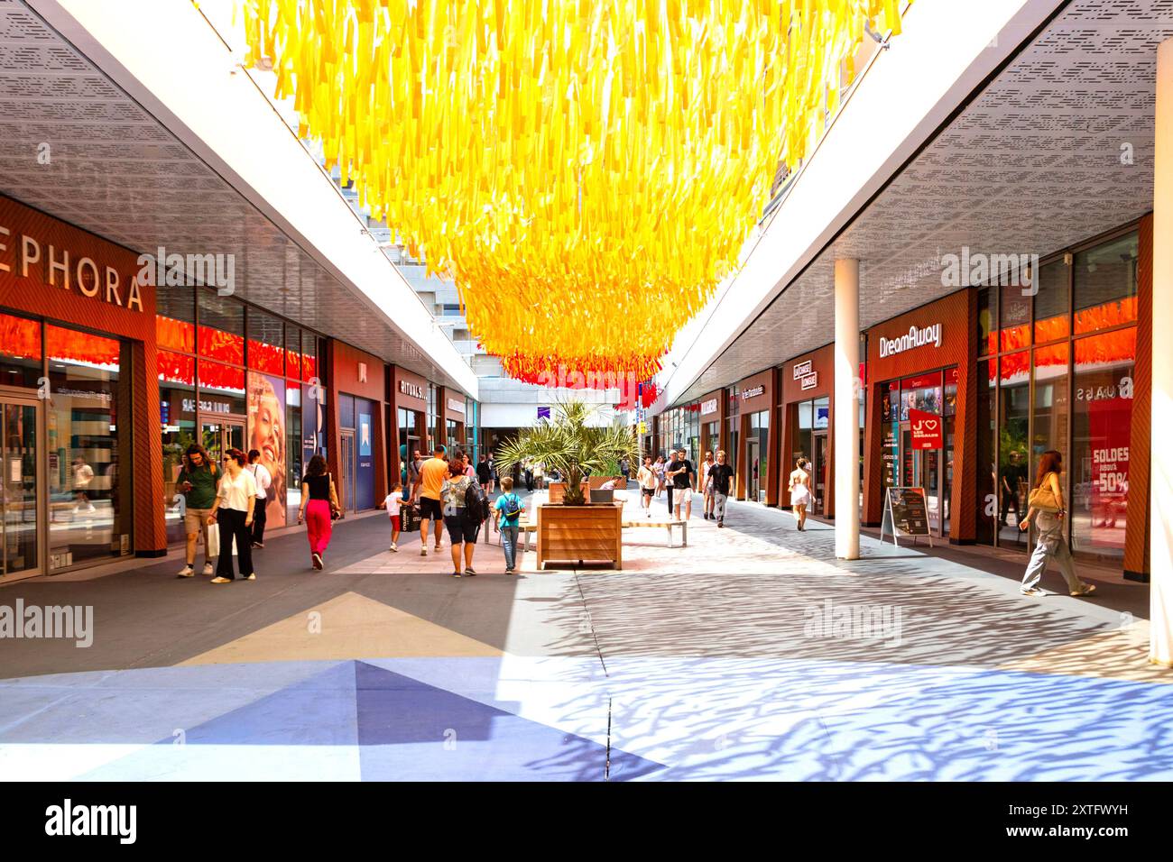 Open-air shopping mall with vibrant yellow decorations and various ...
