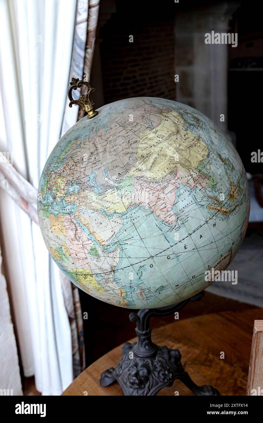An antique globe depicting the world map positioned on a wooden surface ...