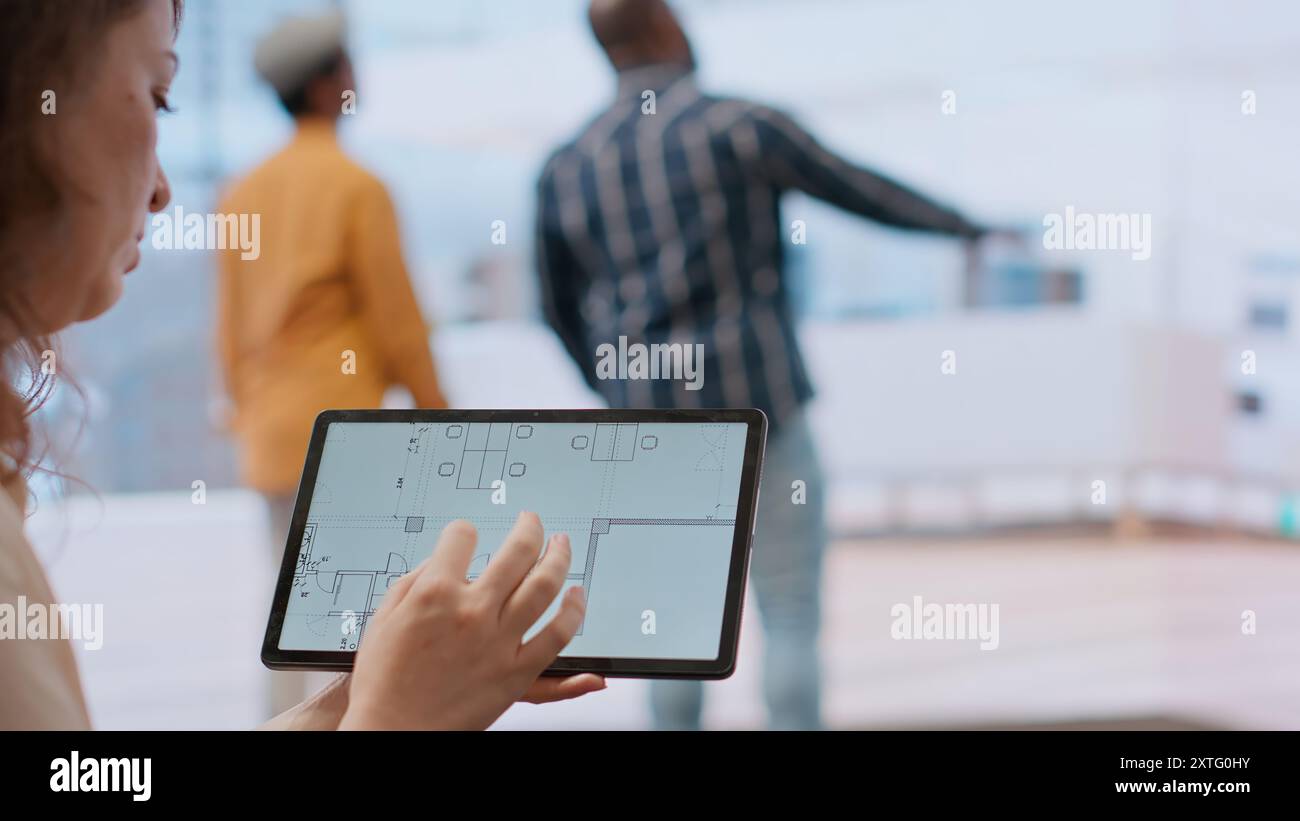 Real estate agent and client evaluating blueprints and discussing the architectural layout of ...