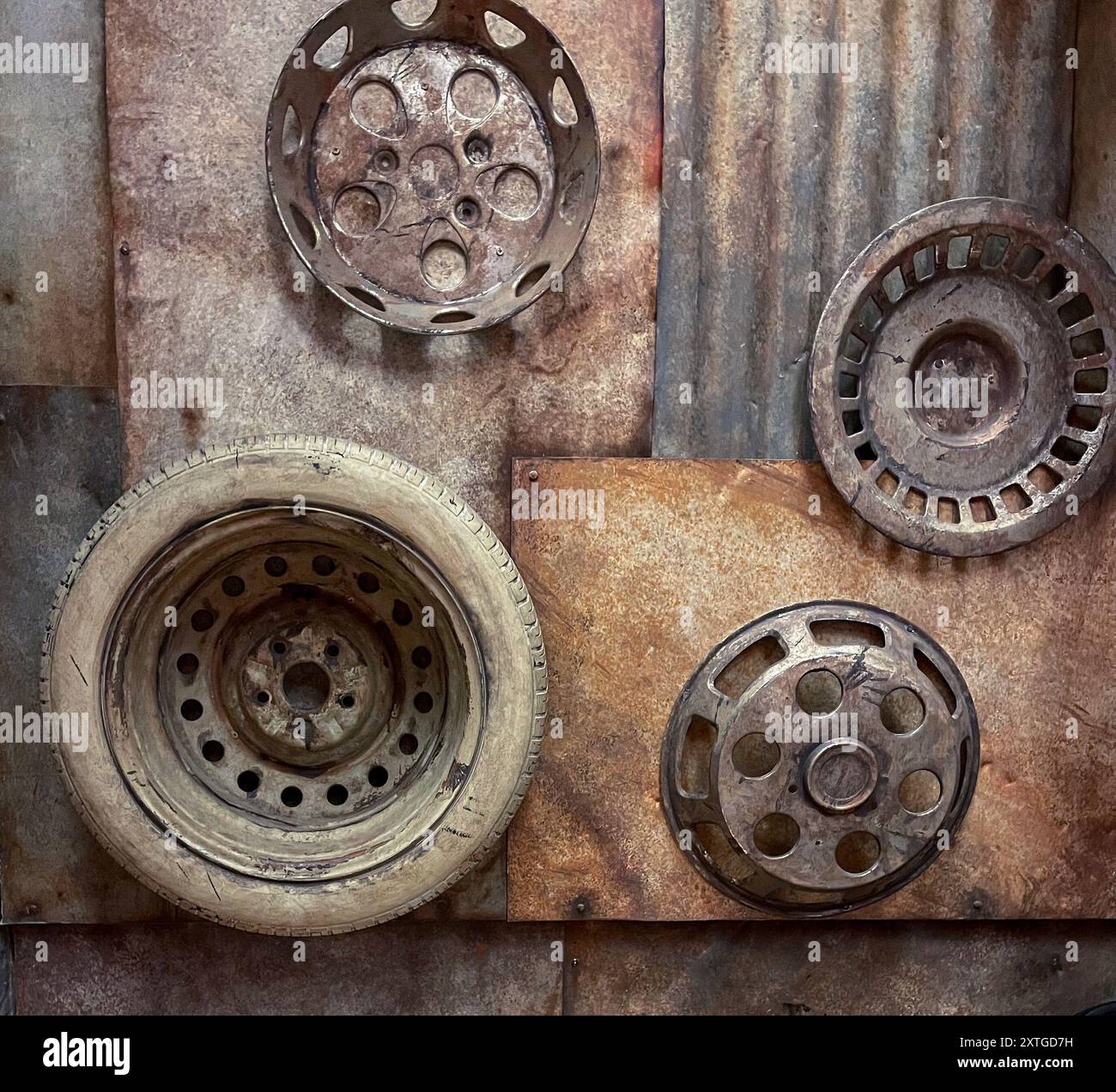 A rustic wall art made from old car wheels and metal sheets creating an ...