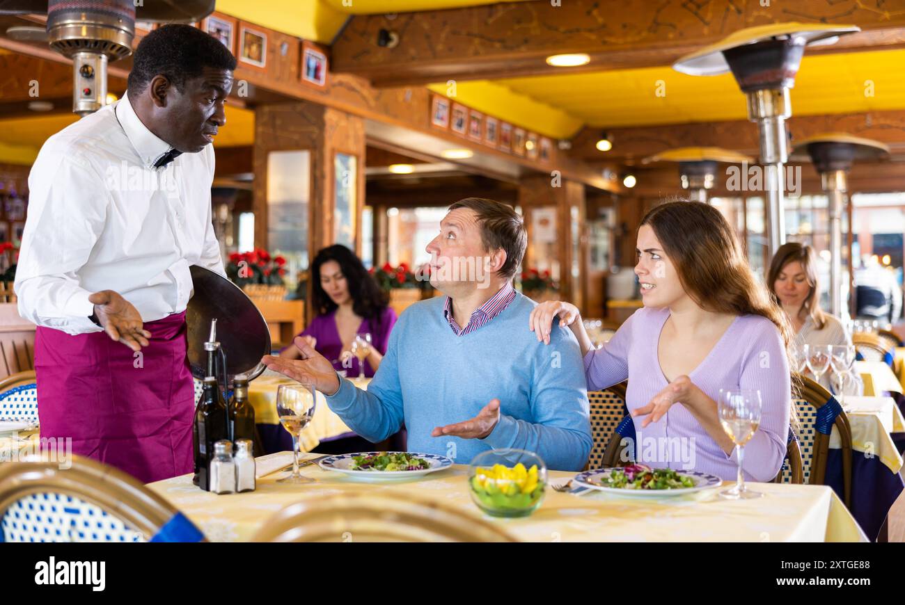 Displeased guests conflicting with waiter Stock Photo - Alamy