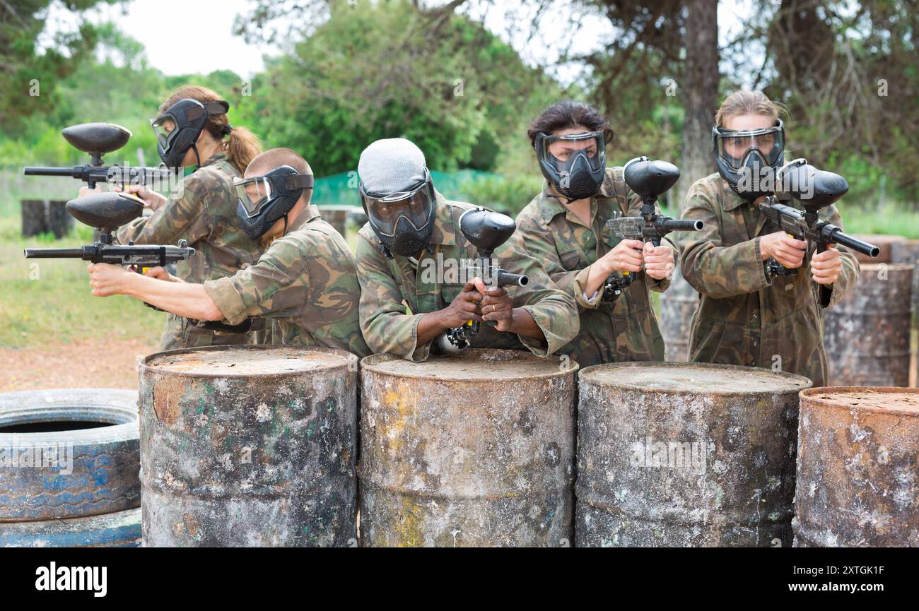 Group of paintball players aiming and shooting with guns Stock Photo ...
