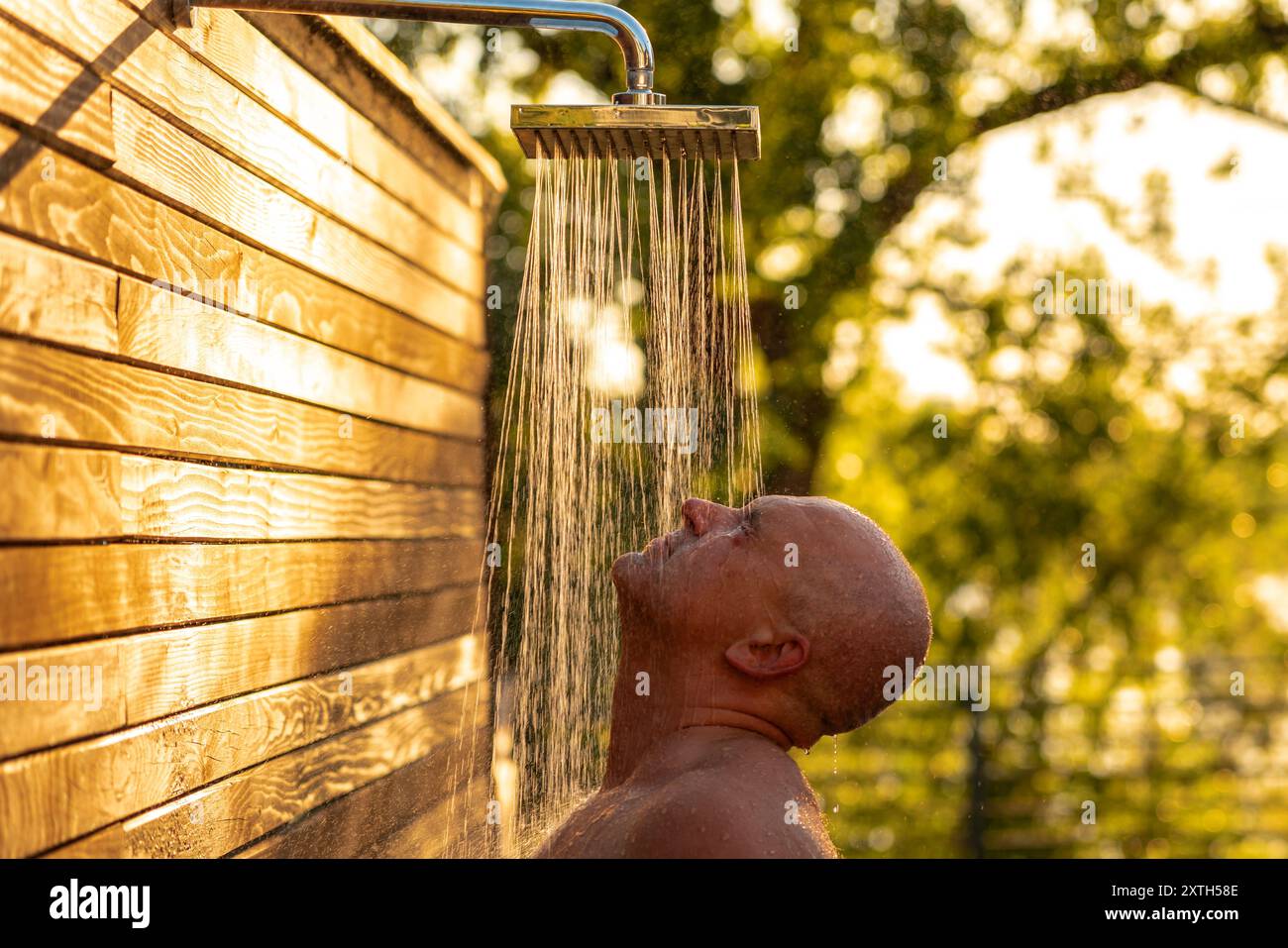 Man enjoying sunset outdoor shower. Concept of relaxation and evening ...
