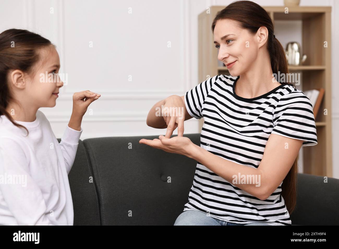 Woman and her daughter using sign language for communication at home ...