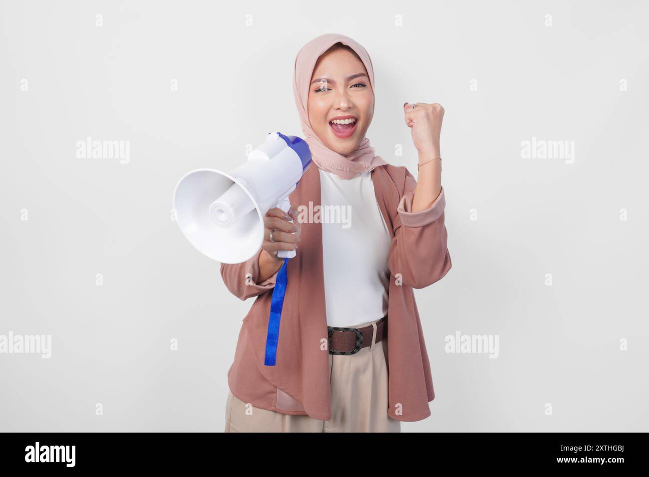 Young Asian Muslim woman wearing hijab shouting at megaphone with happy ...