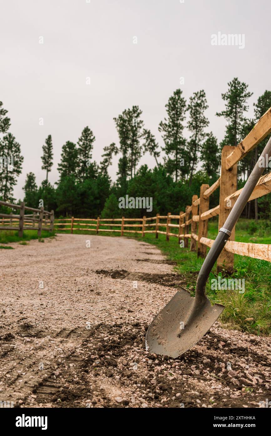 Shovel leaning against a wooden, split-rail fence. Fence and road ...