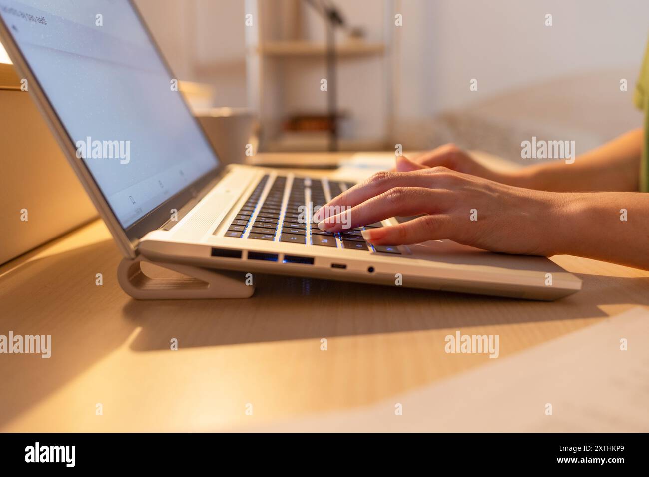 Side view of laptop on desk in home office. Hands types on keyboard ...