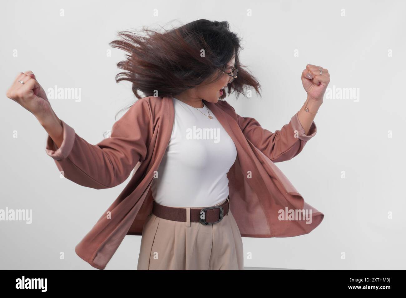 Cheerful young Asian woman in doing a successful win gesture with ...
