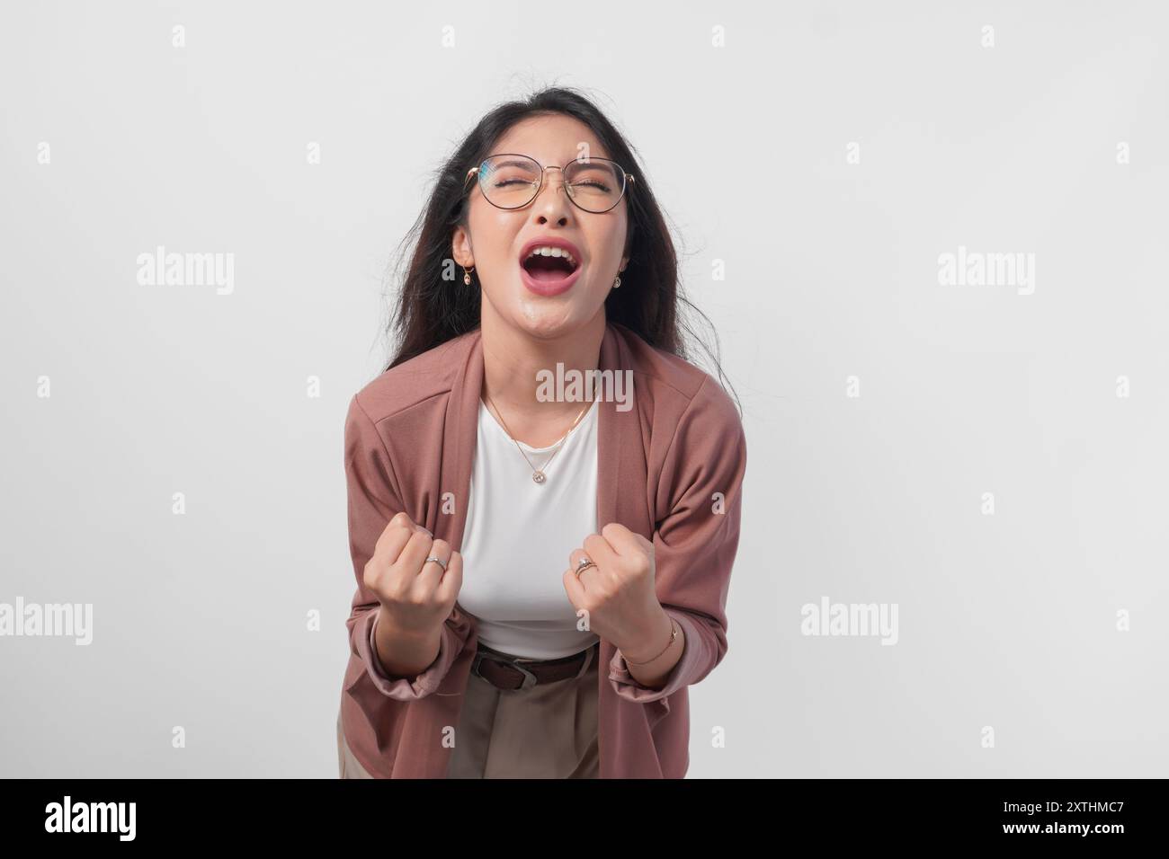 Cheerful young Asian woman in doing a successful win gesture with ...