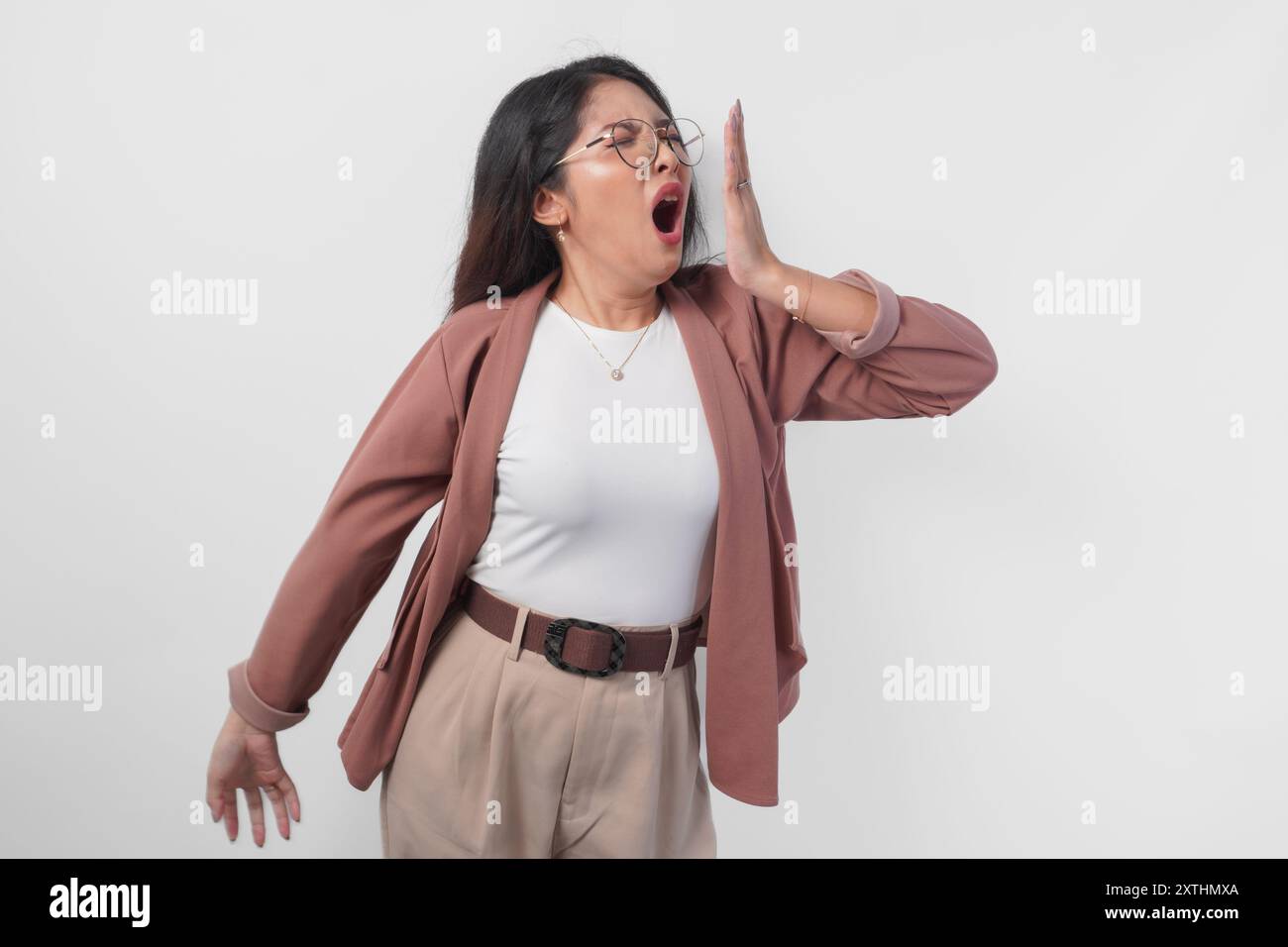 Sleepy young Asian woman wearing eyeglasses yawning over isolated white ...