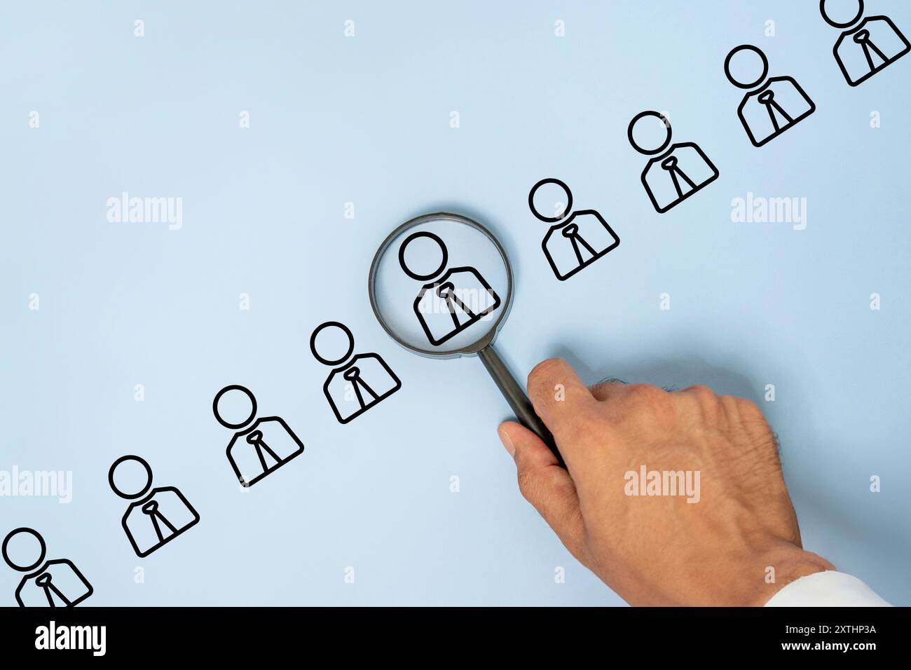 A hand holding a magnifying glass focuses on a single person icon in a ...