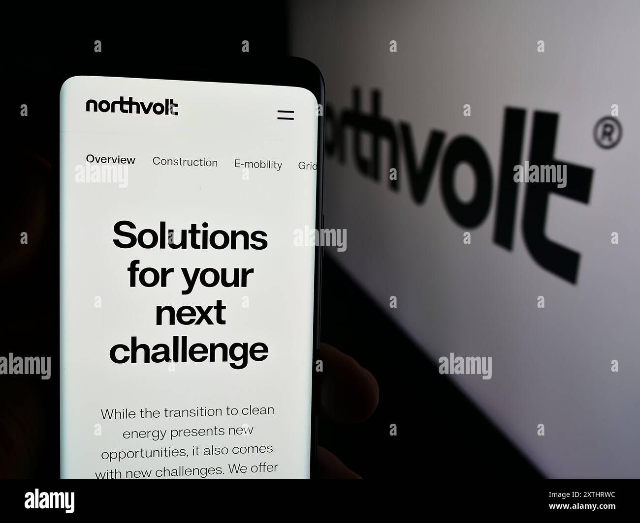 Person holding cellphone with webpage of Swedish battery company ...