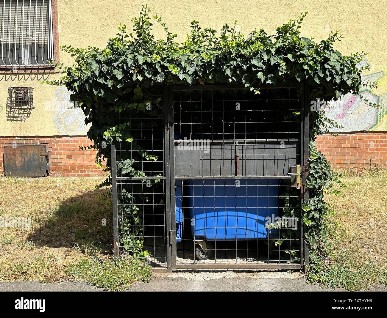 Garbage can behind the metal door Stock Photo - Alamy