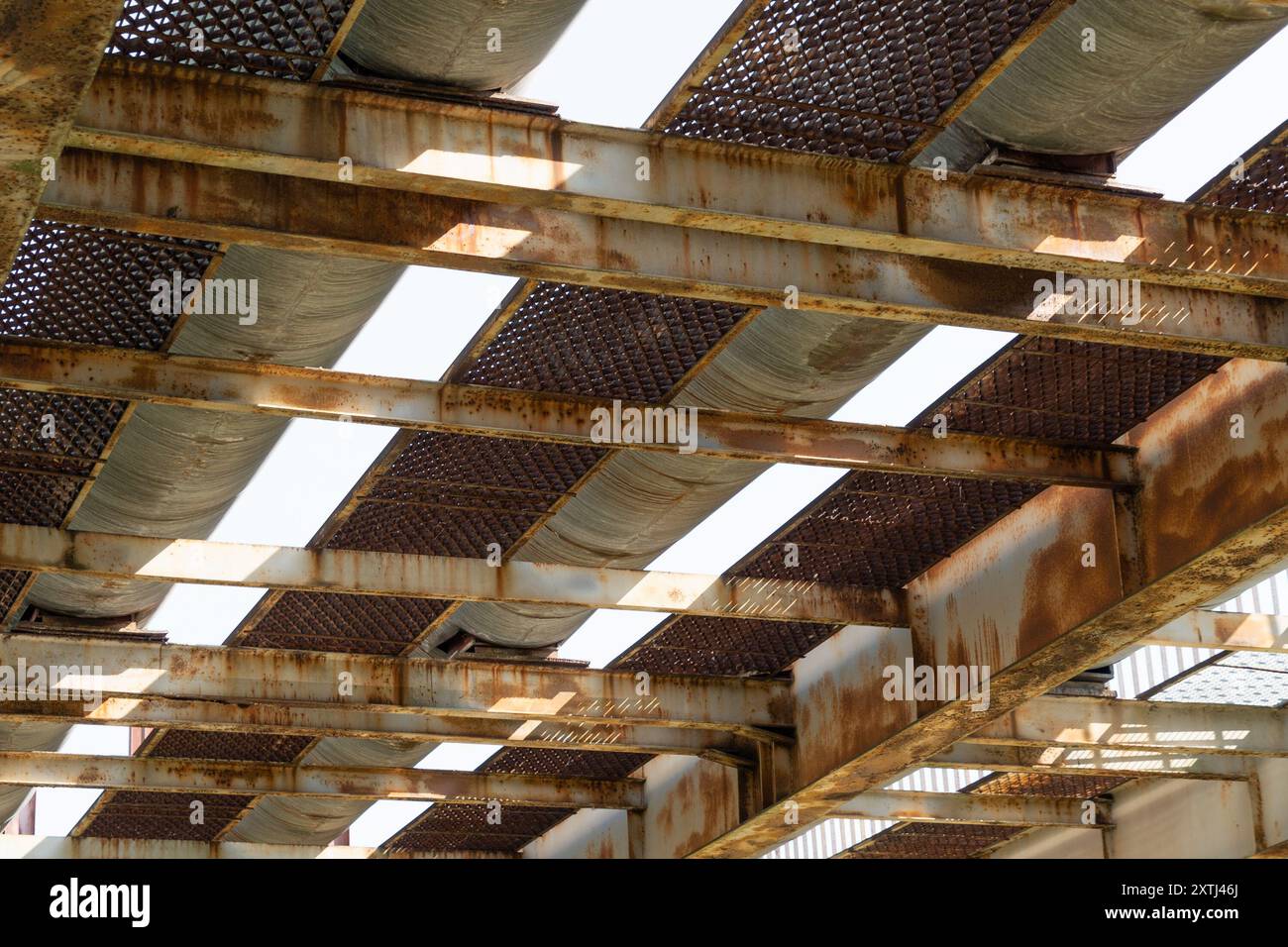 Rusty steel beams and metal grates under an industrial structure. Under ...