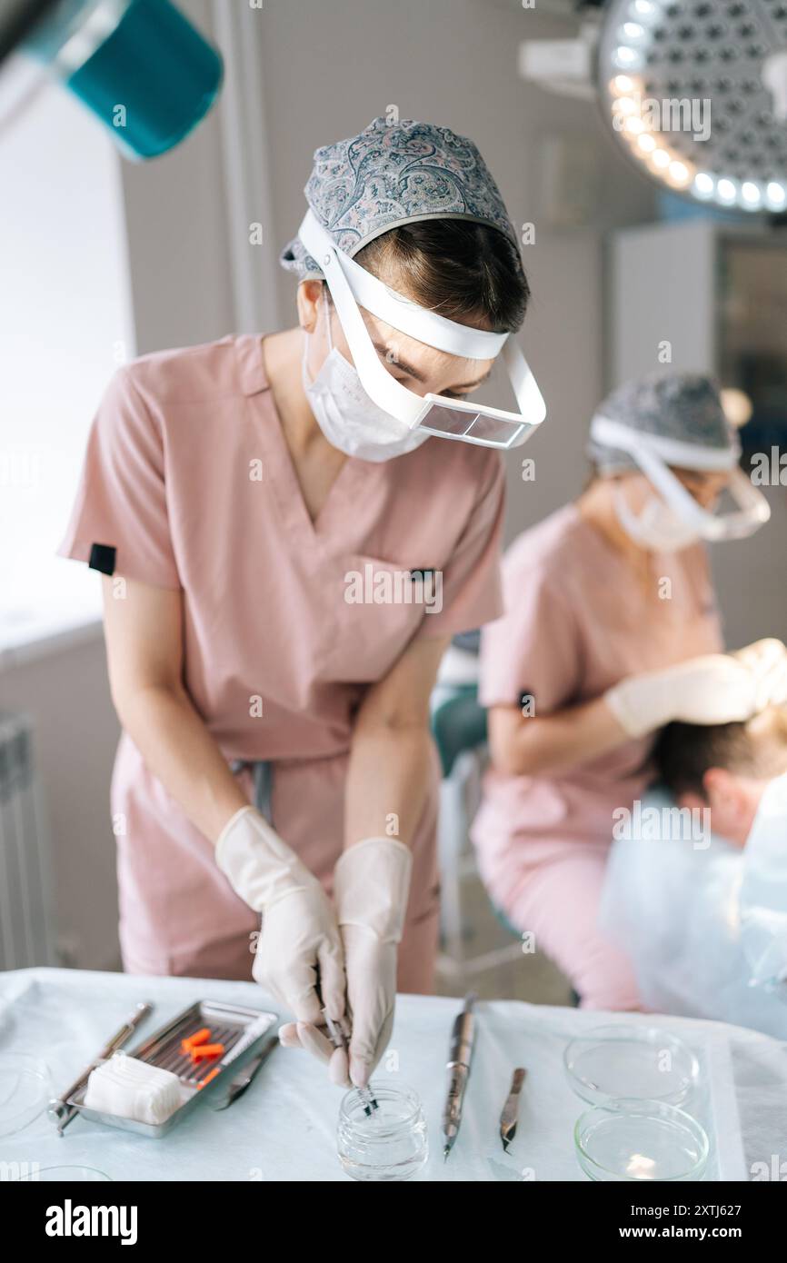 Vertical portrait of female doctor in gloves and mask fill in syringe ...