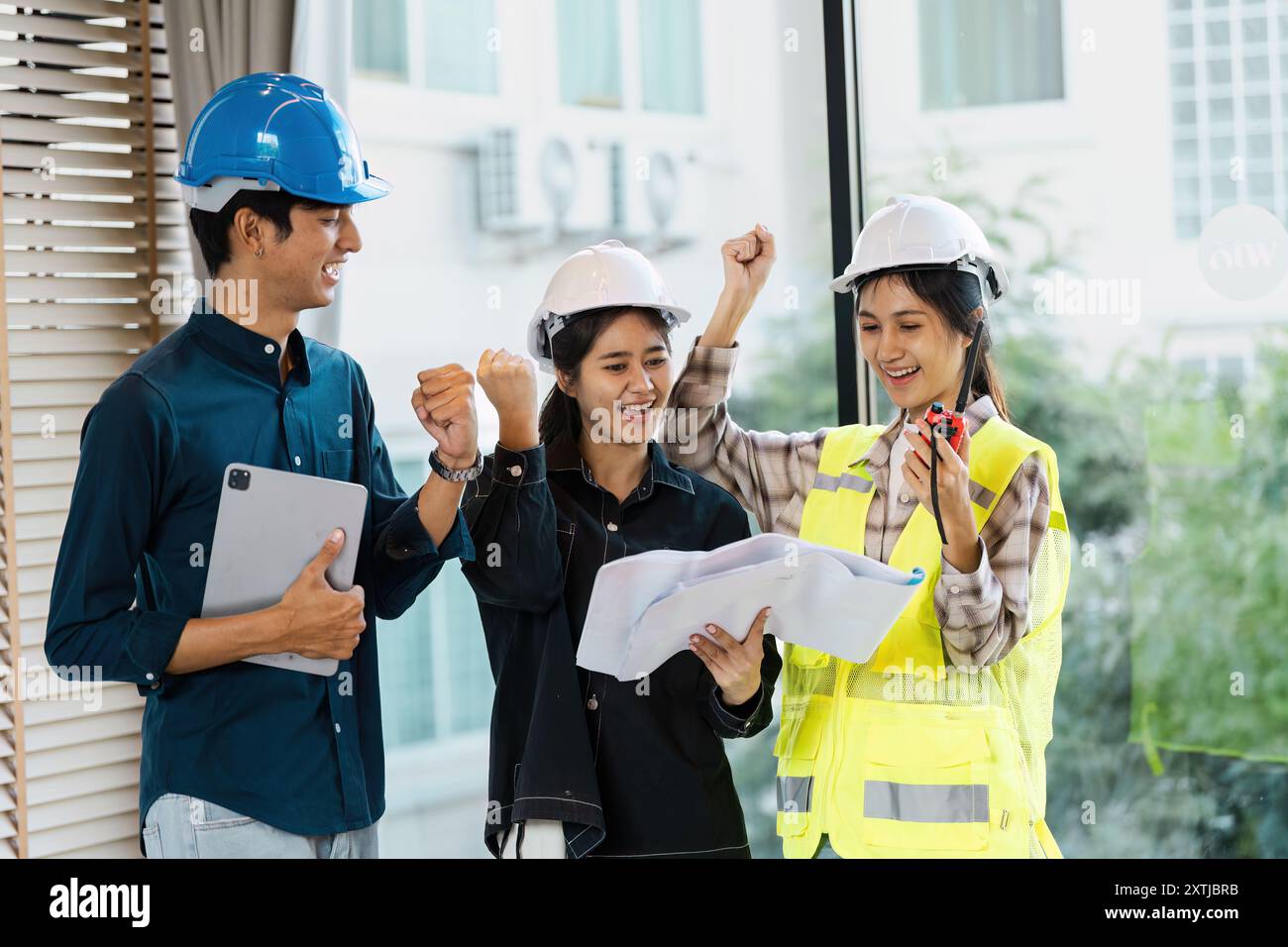 Group of Happy Engineer Celebrating Success with Blueprint in Hand at a ...