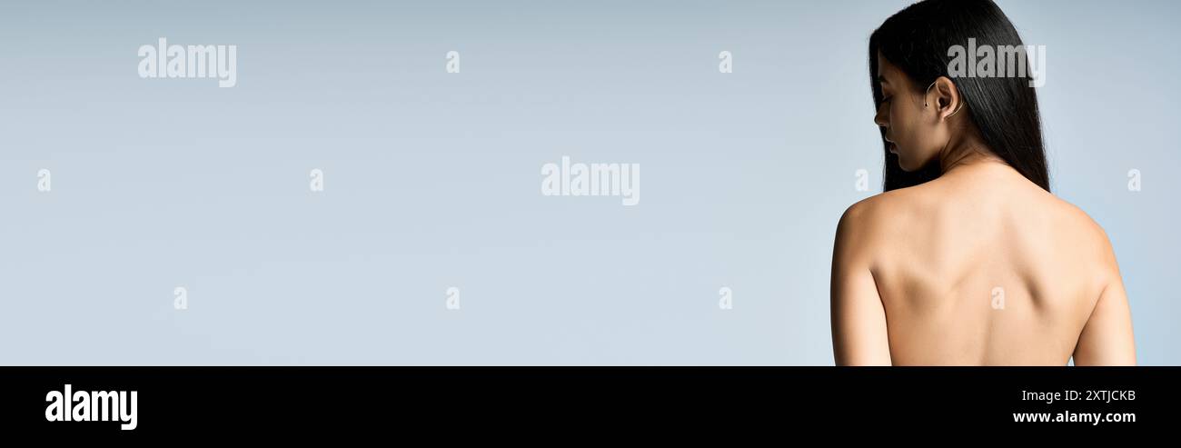 A young woman stands with her back to the camera, her long hair ...