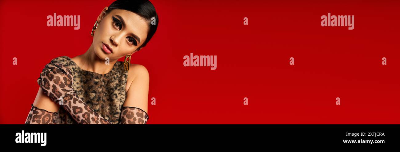 A young woman wearing a leopard print outfit poses against a bright red ...