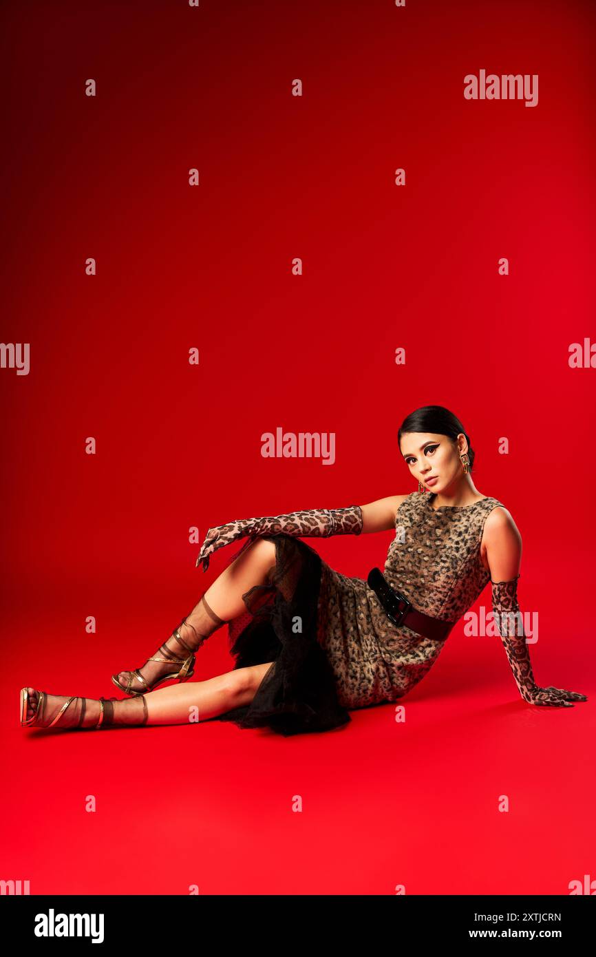 A young woman in a leopard print dress poses with stylish gloves on a ...