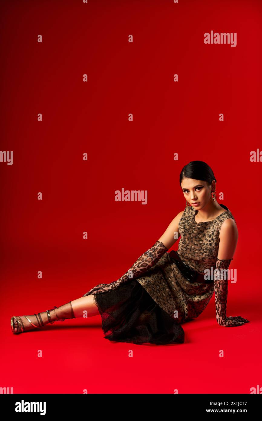 A young woman in a leopard print dress and matching gloves poses on a ...