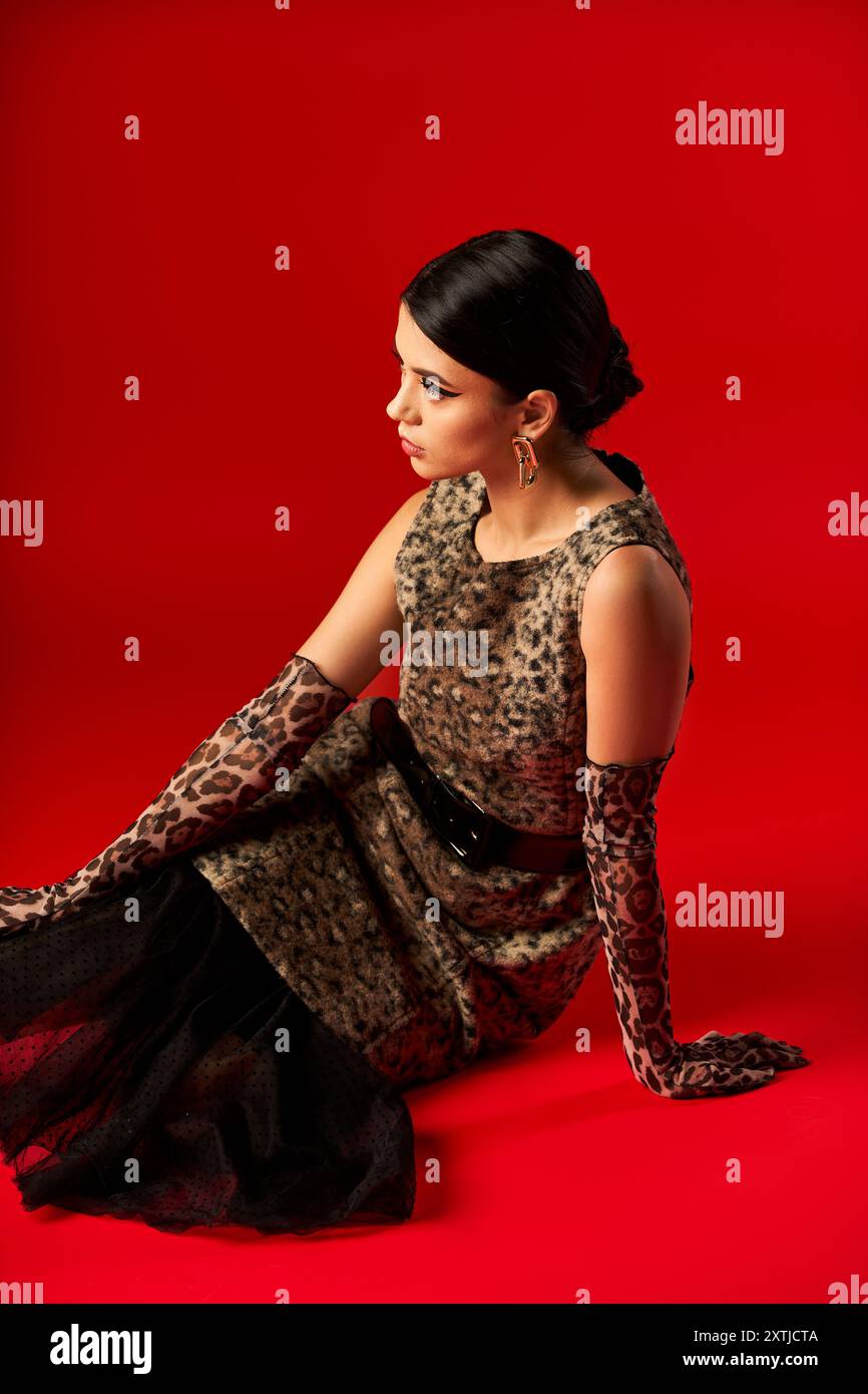 A young woman in a leopard print dress poses on a red background Stock ...