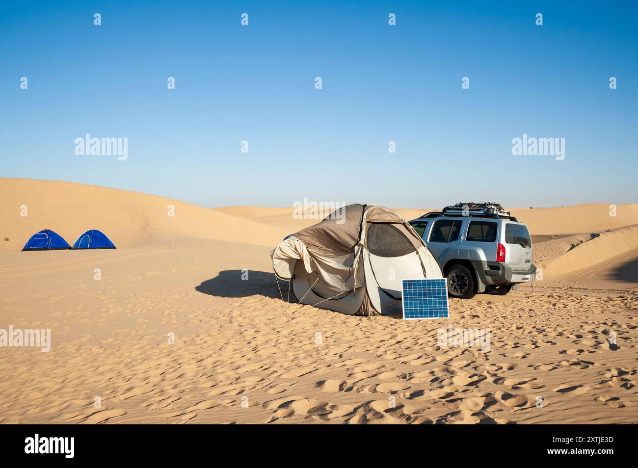 Off-road car, three tents, and solar panel setup in a vast desert ...