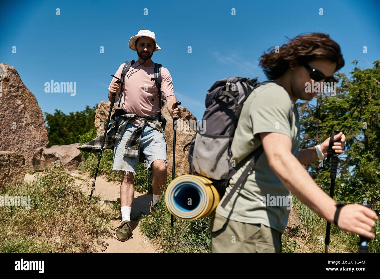 Two young men, a gay couple, are hiking through a scenic wilderness ...