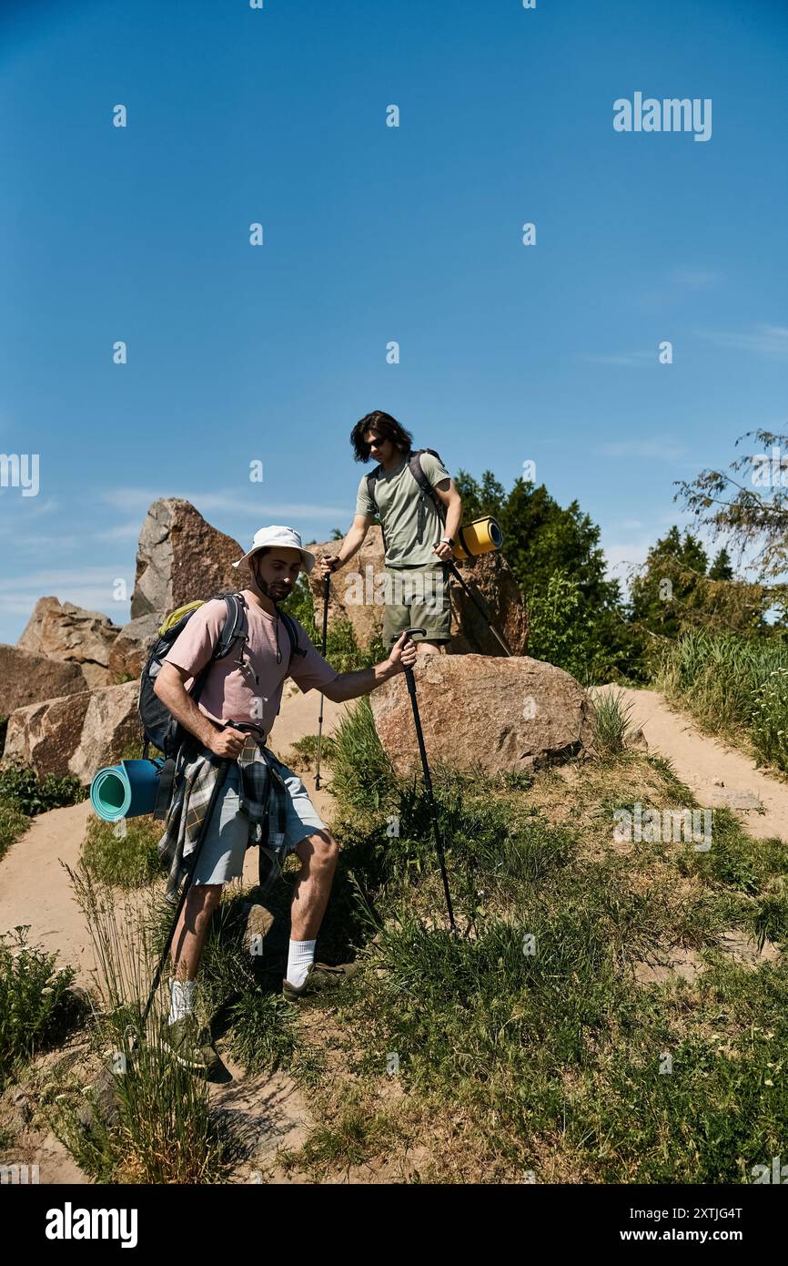 Two young men are hiking together in a rocky landscape. They are both ...
