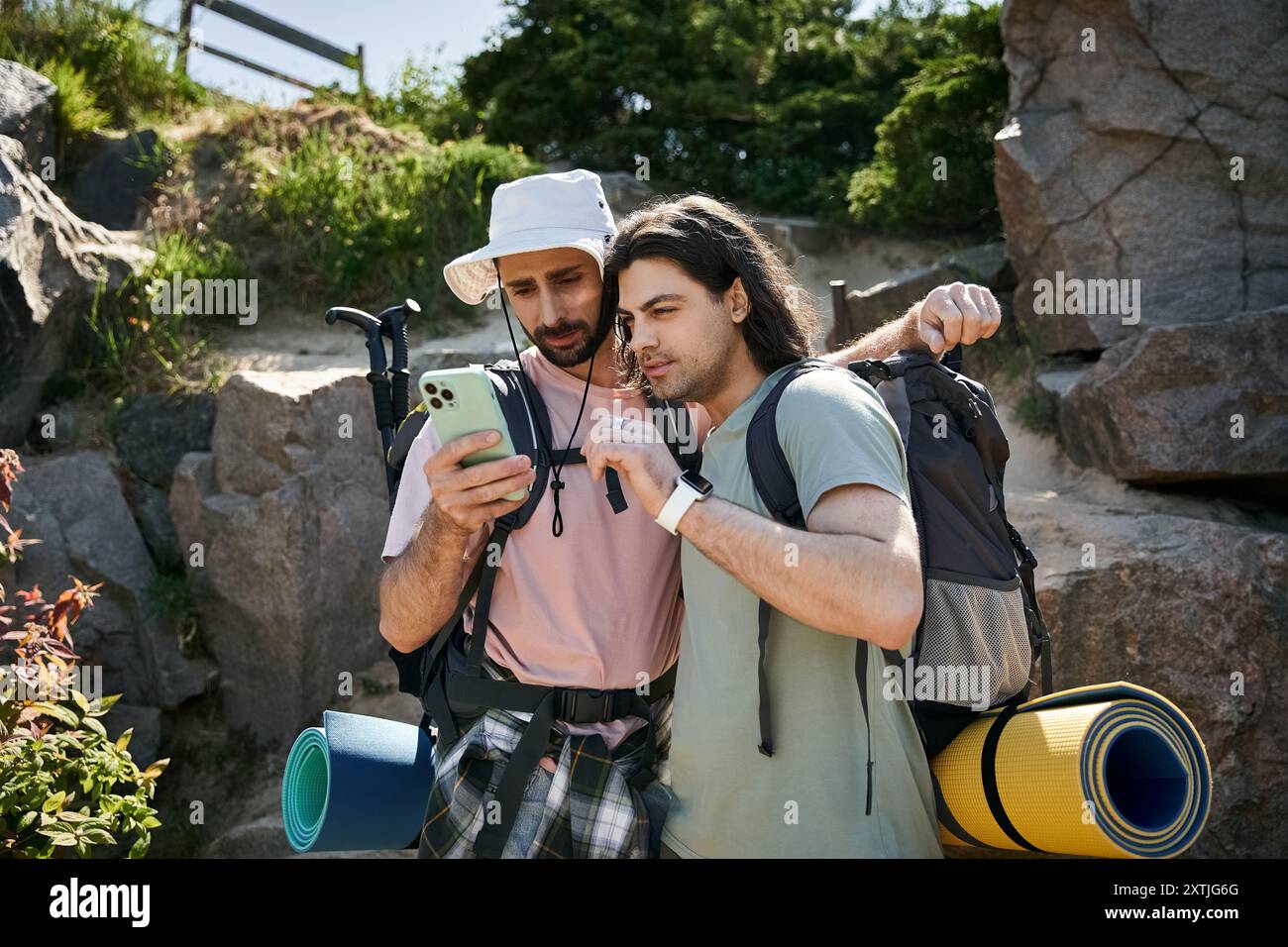 Two young men, a gay couple, hike through nature on a sunny day ...