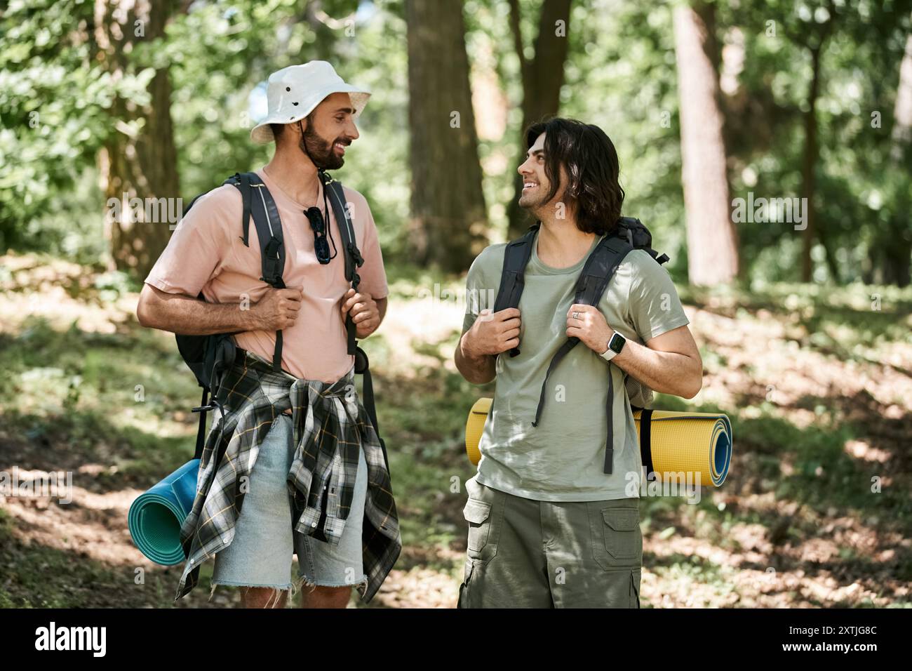 A gay couple hikes through a lush green forest, enjoying the summer sun ...