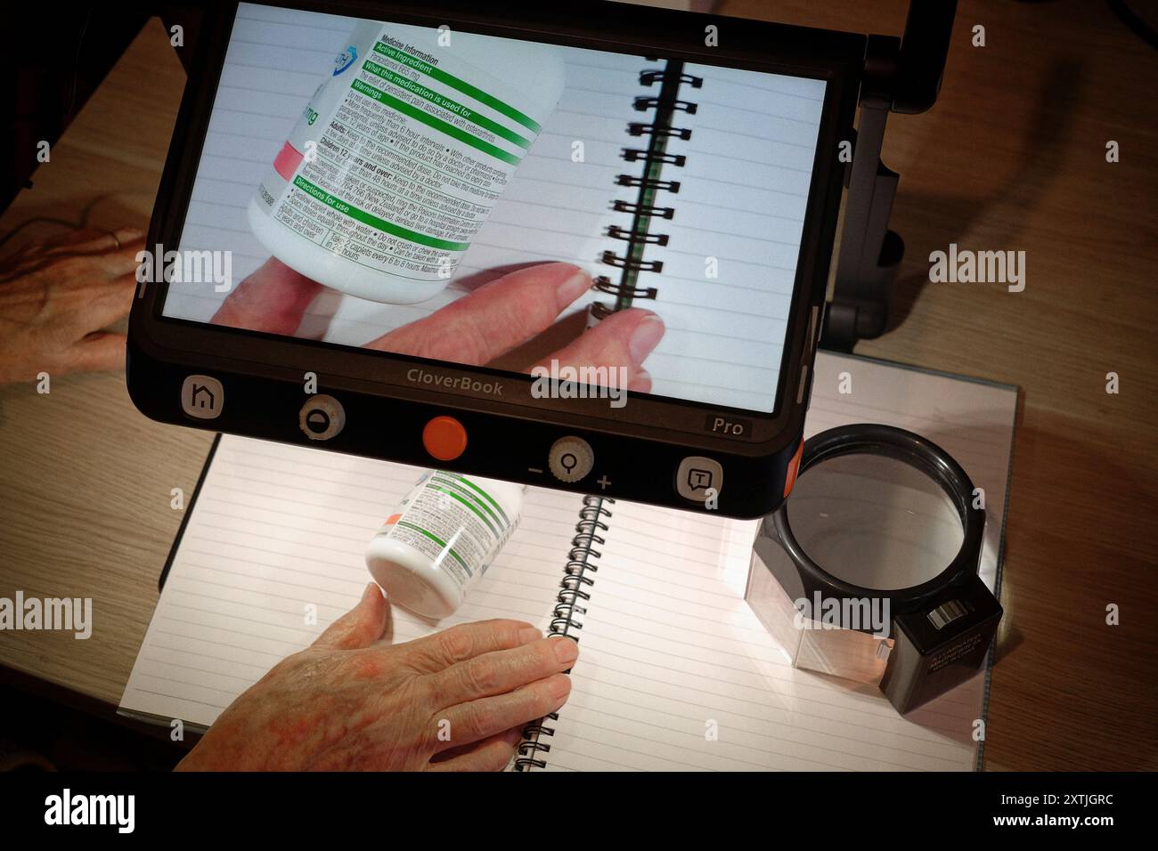 A senior woman uses a low vision reading aid magnifier for reading the ...