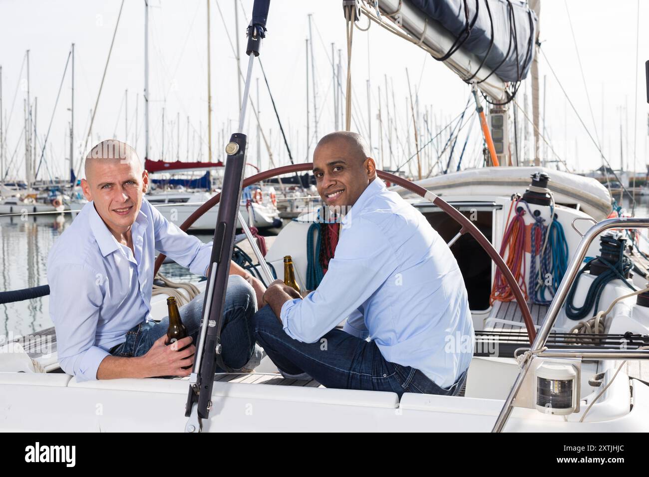 Two men in blue shirts relaxing on sailing yacht in the port Stock ...