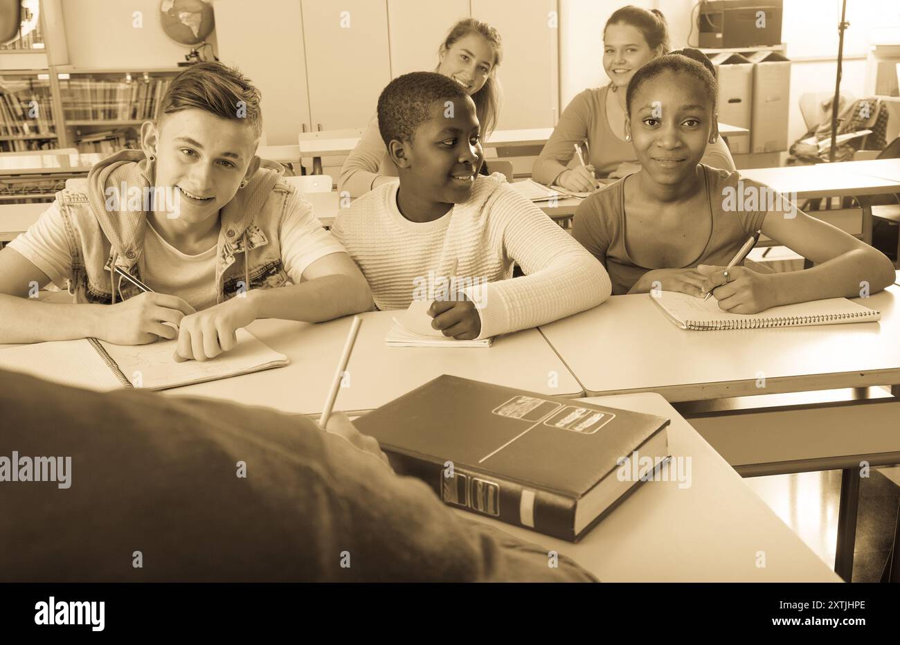 Smiling students sitting at their desks in classroom Stock Photo - Alamy
