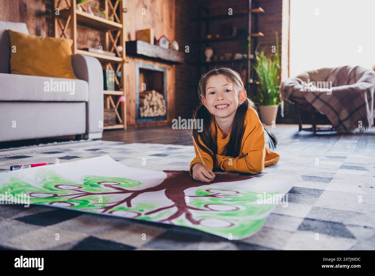 Full body photo of nice little girl lying floor drawing family tree ...