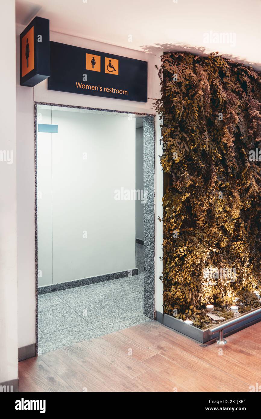 A well-lit entrance to a women's restroom with a modern sign, located ...