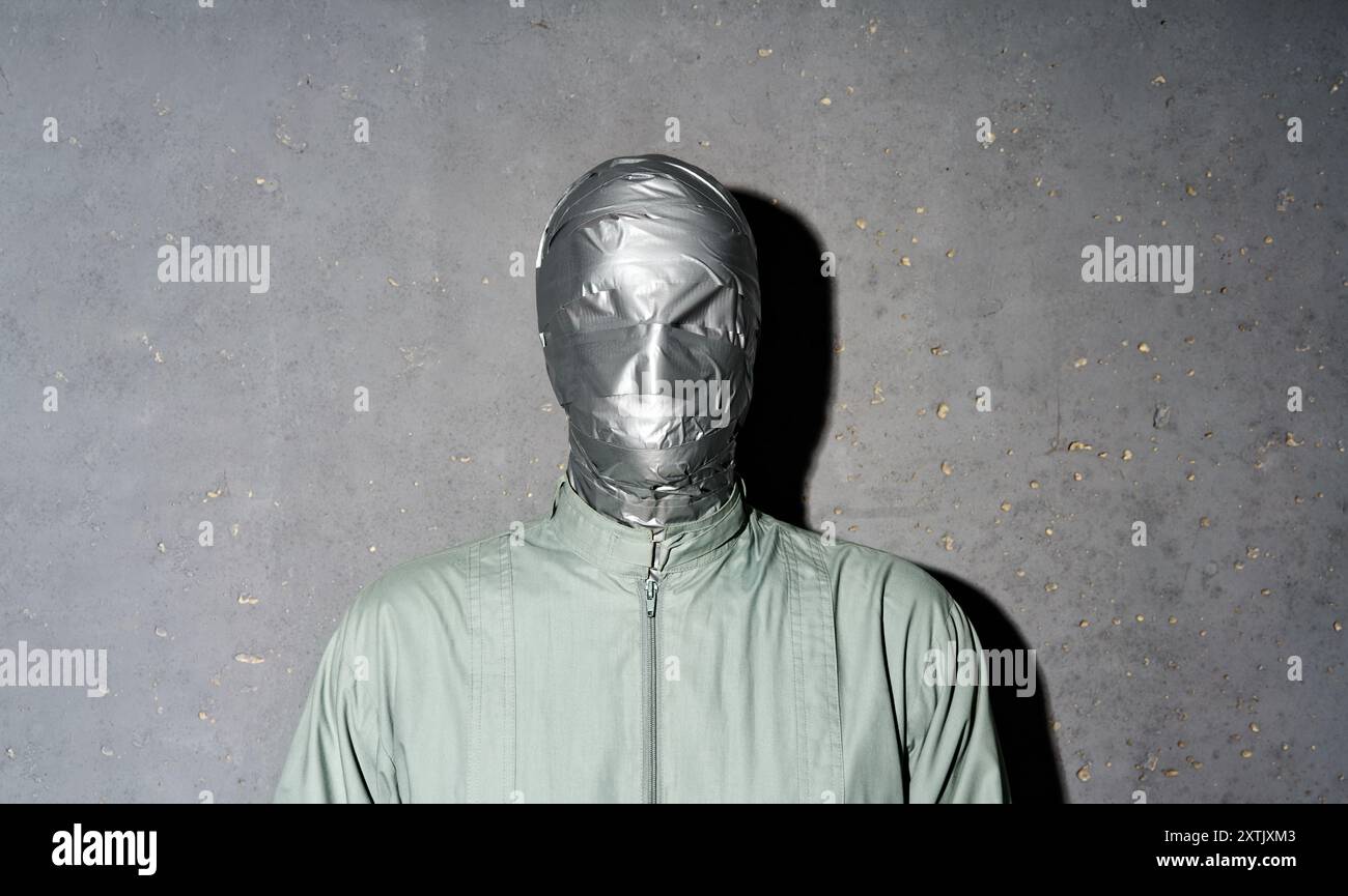 Mystery man with duct tape face wrap on gray background. Horror, secret ...