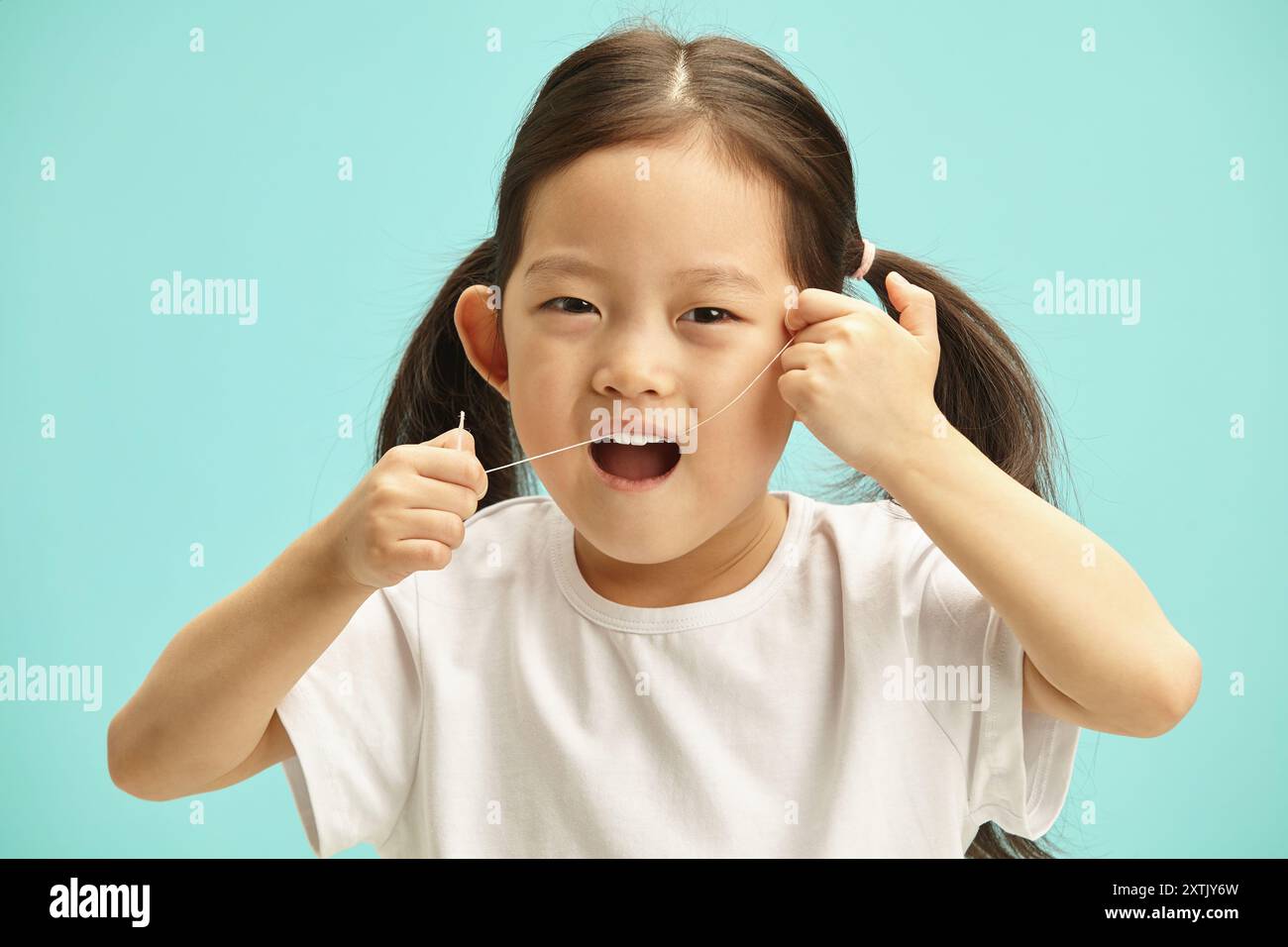 Sweet female child cleans herself teeth using dental floss with soft ...