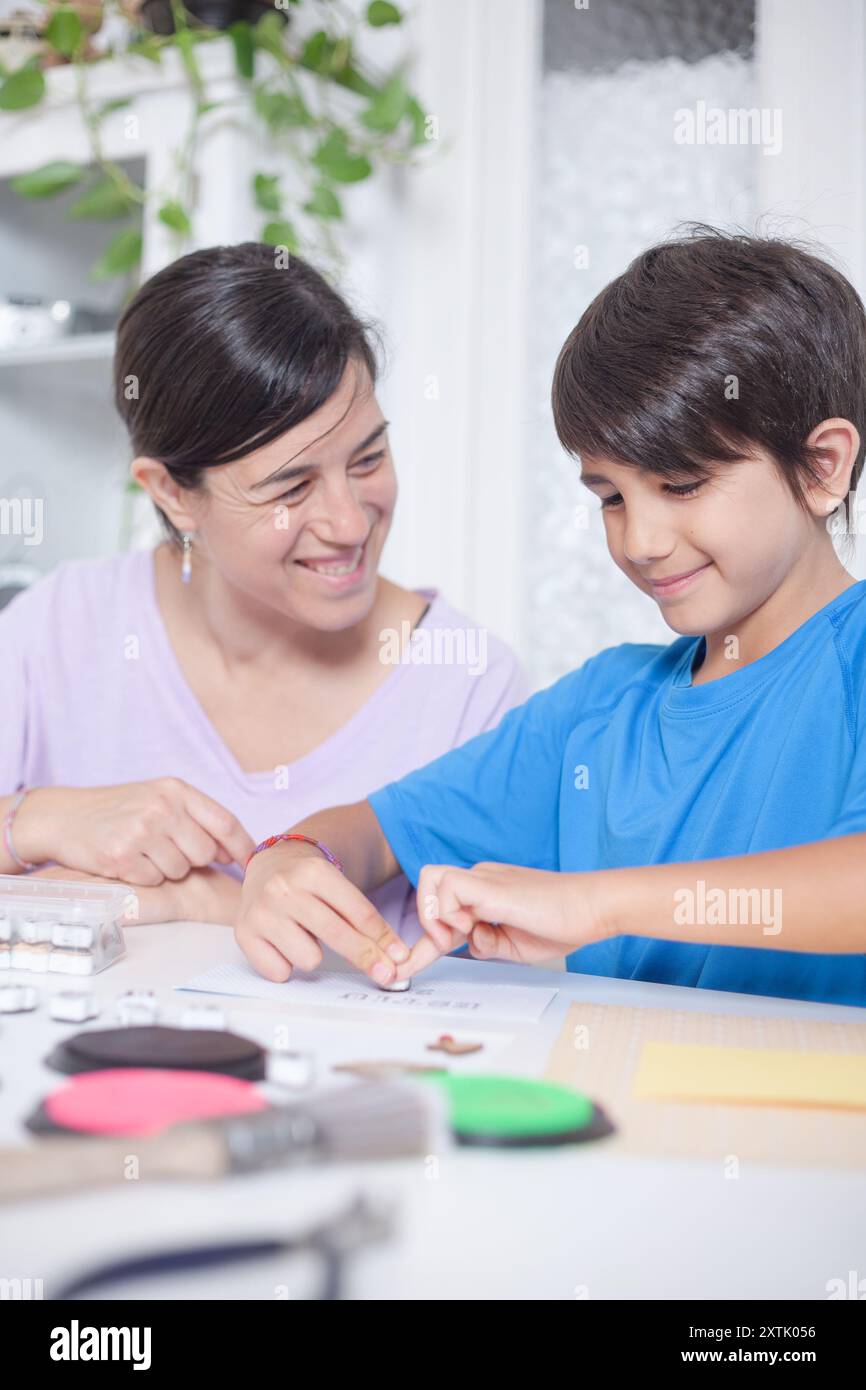 Woman looks at kid smiling as he makes a craft. Family, crafts and ...