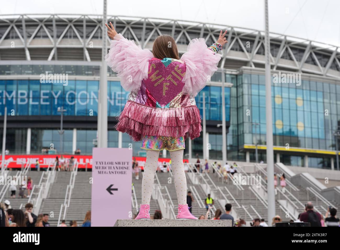 A young fan with a sparkly, decorated jacket reading Swiftie poses ...