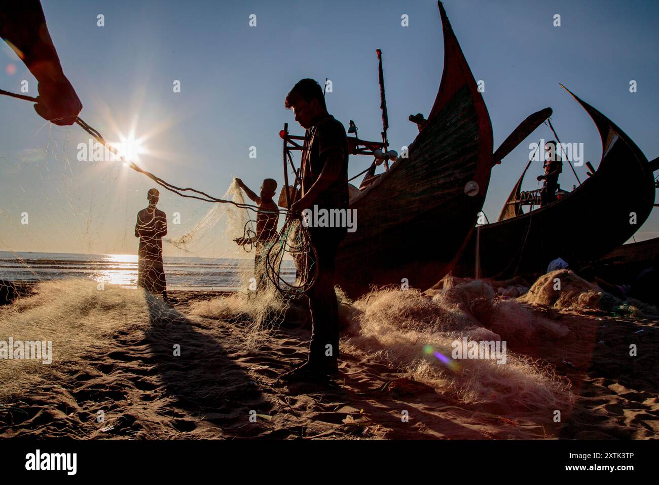 Fishermen prepares the fishing nets ahead of the next high tide. The ...