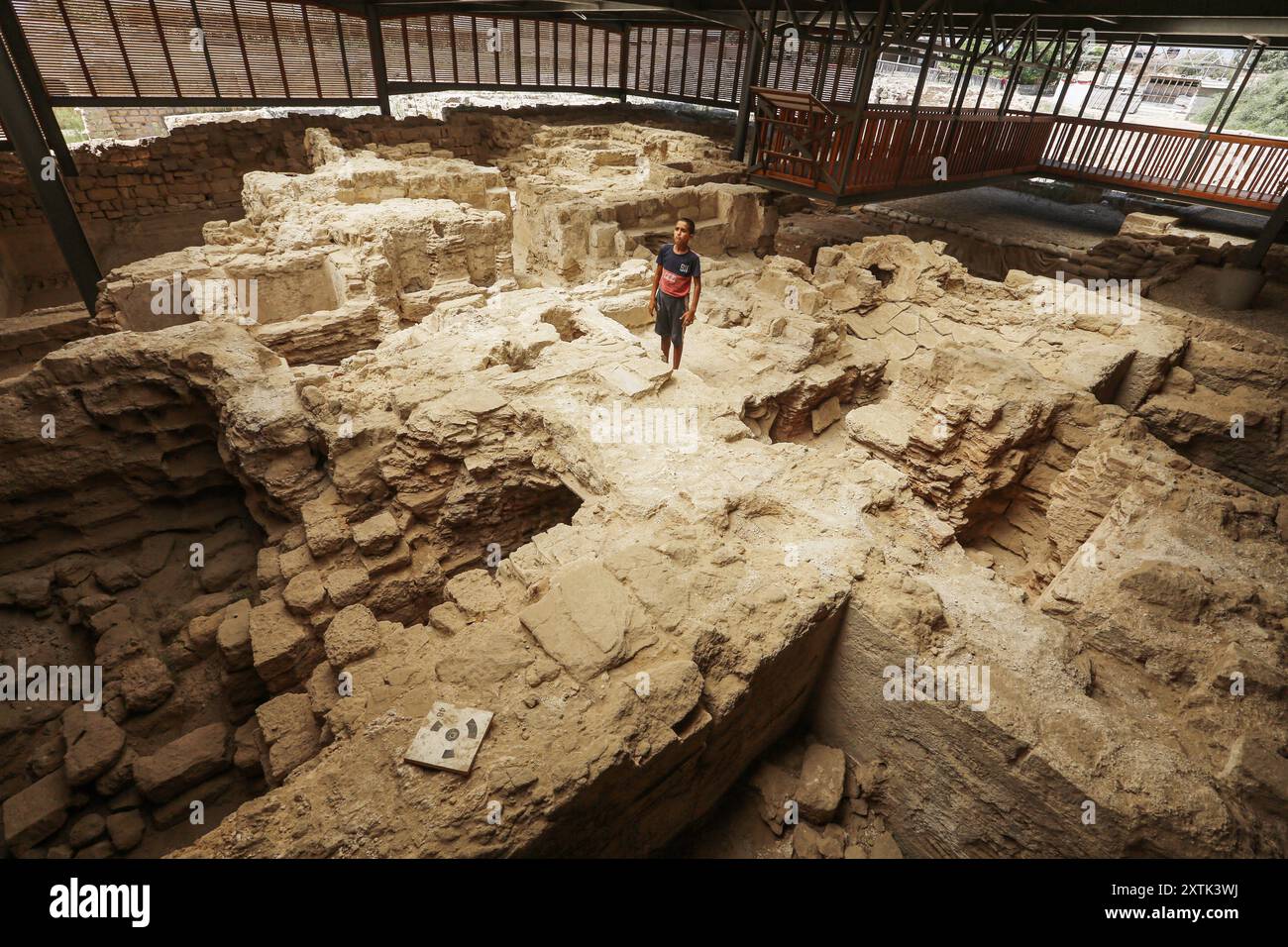 People stand on a platform overlooking ruins at the archaeological site ...
