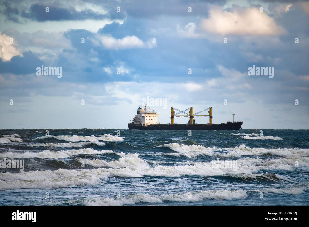 Cargo ship sailing through turbulent ocean waves against a backdrop of ...