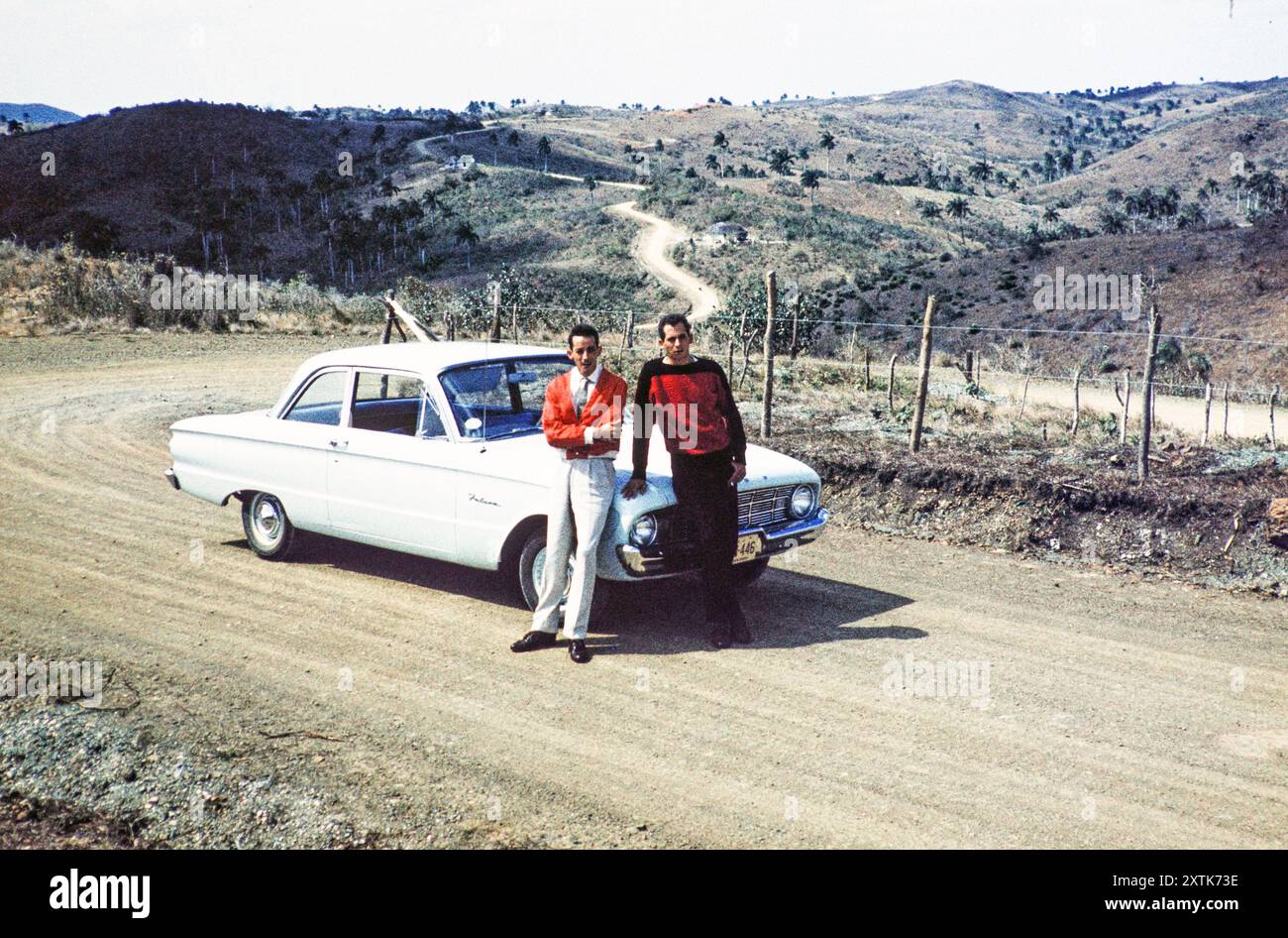 Two men standing by Ford Falcon car in undulating countryside rural ...