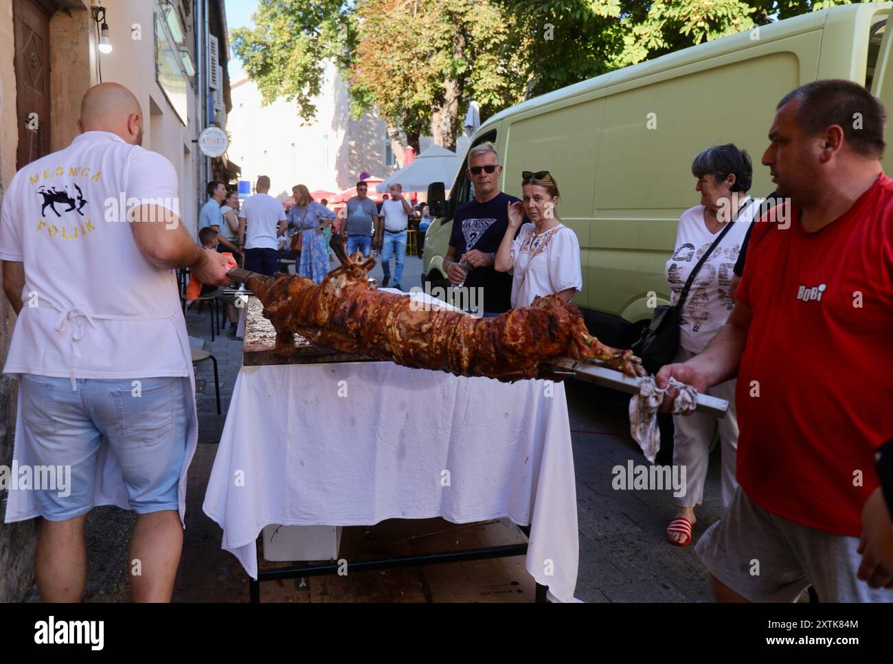 Sinj, Croatia. 15th Aug, 2024. Vendors sell spit roast pork during a ...